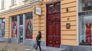 Um edifício com a placa do Hotel UNO Design, uma porta vermelha e um manequim vestido de vermelho.