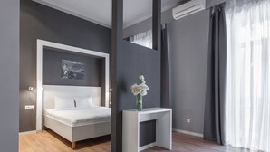 Quarto moderno com cama, mesa de cabeceira, ar condicionado fixado na parede e janela com cortinas.