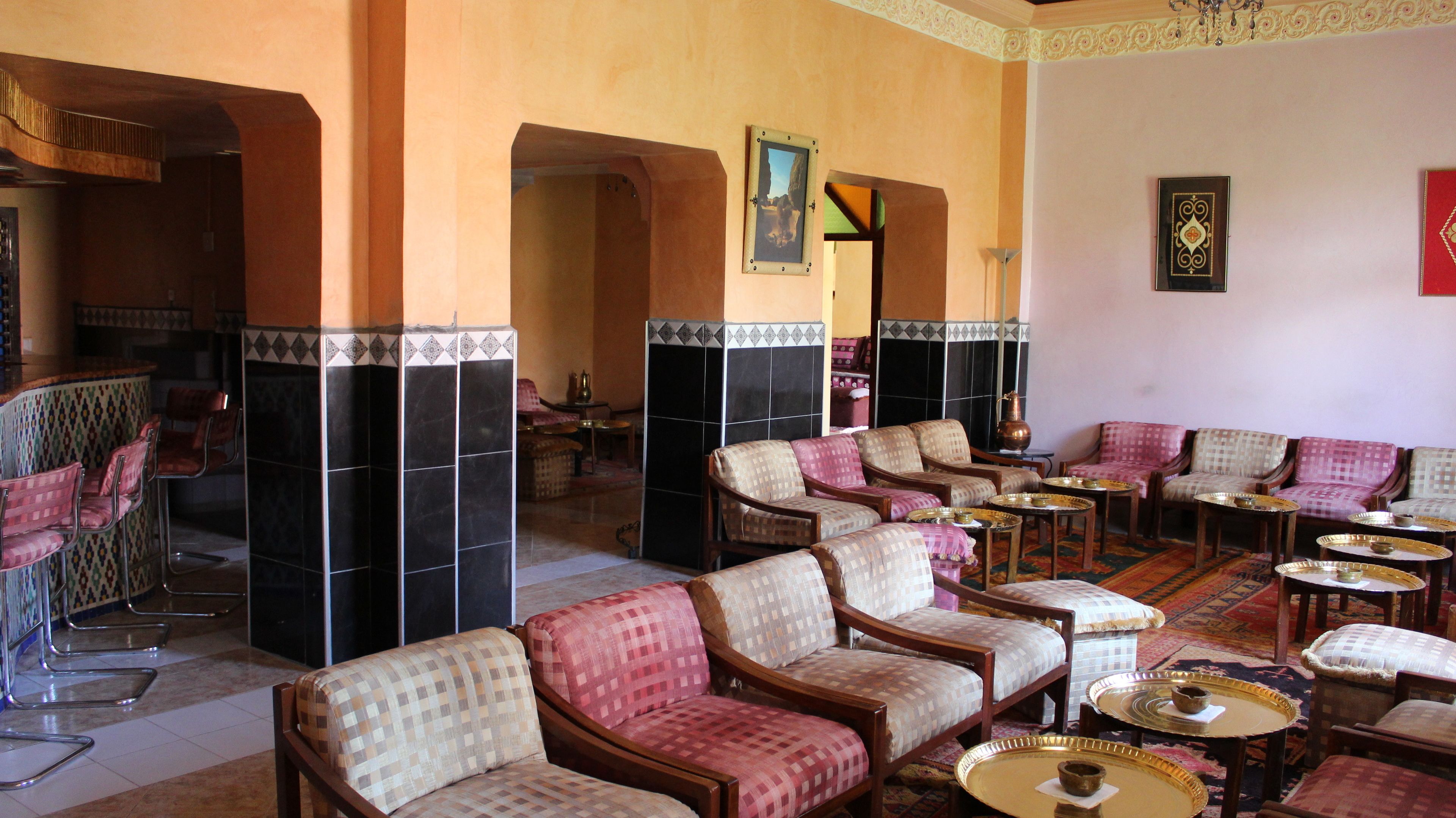 Uma sala de estar ampla com várias opções de assento, incluindo sofás e poltronas, dispostas ao redor de mesas baixas com bandejas.