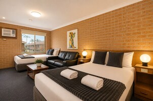 Quarto de hotel com uma cama grande, um sofá, uma mesa de escritório e uma janela com vista.