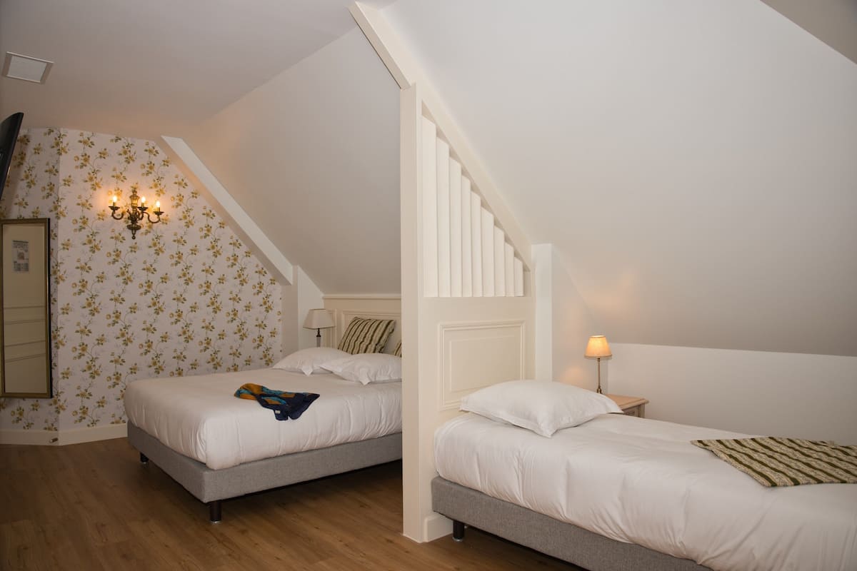 Quarto com duas camas, uma escada e um candelabro.
