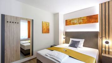 Quarto de hotel moderno com uma cama grande, um espelho, uma mesa de cabeceira e uma luminária.