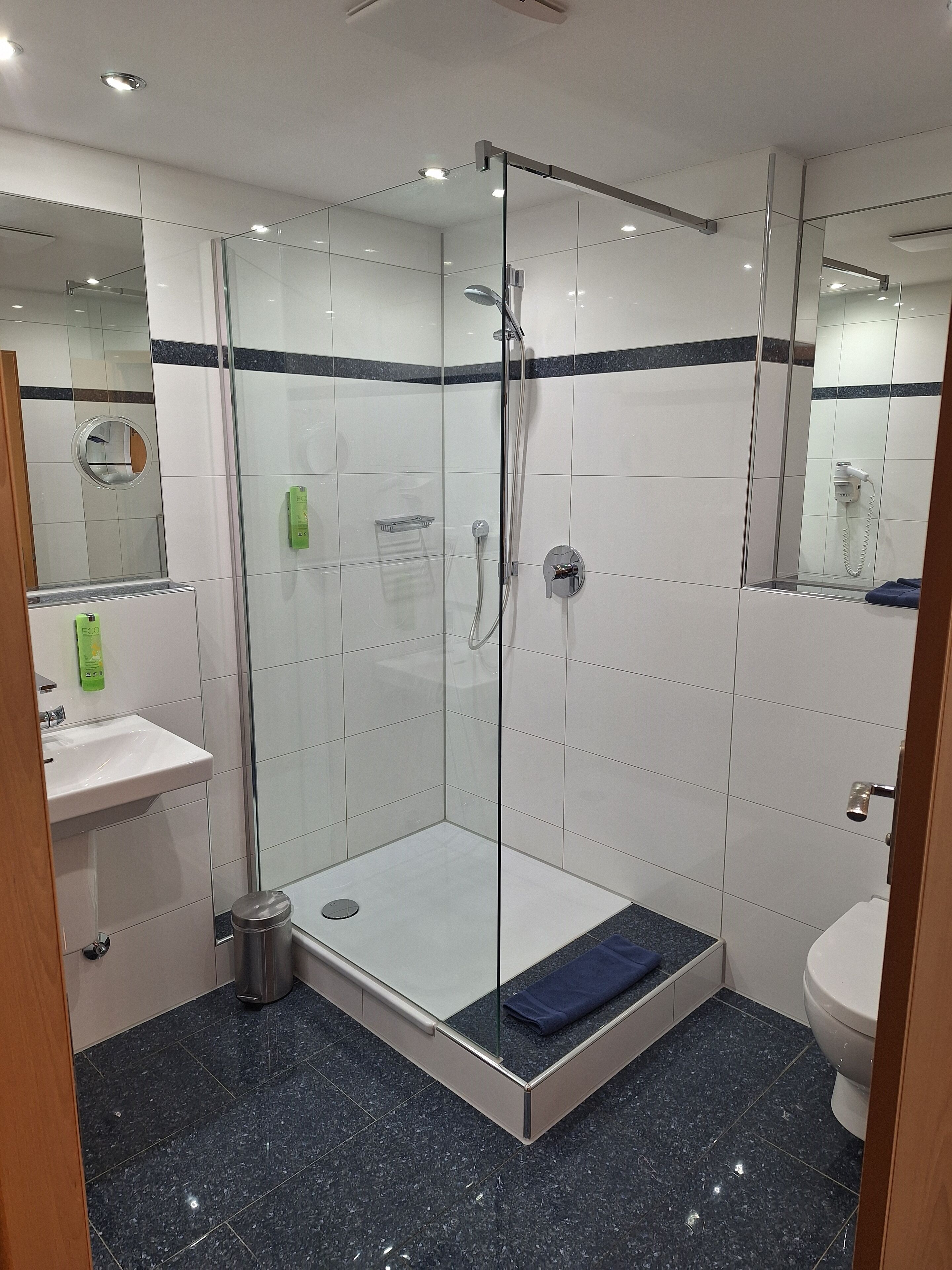 Uma casa de banho moderna com chuveiro de vidro, lavatório branco e sanita.