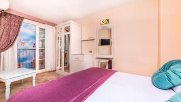Quarto com cama, escrivaninha, guarda-roupa e televisão.