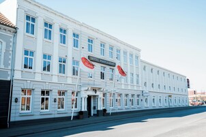 Um edifício branco com uma placa que diz 'HOTEL POSTGAARDEN'.