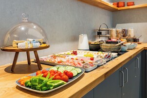 Uma mesa de buffet com diversos pratos e uma cúpula de vidro sobre algumas opções.