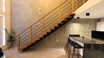 Uma cozinha moderna com escada de madeira, área de bar e parede de concreto como detalhe.