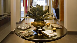 Uma mesa redonda com um candelabro, uma planta em vaso, alguns livros e velas.