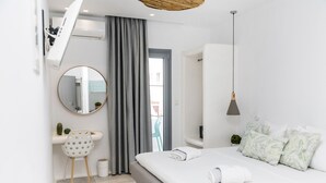 Quarto moderno com cama, espelho redondo, cadeira branca pequena e janela com cortinas.