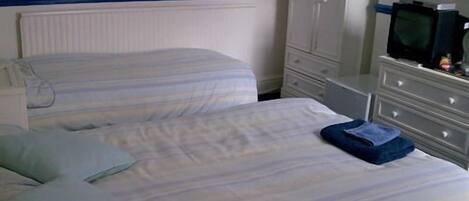 Quarto de hotel com duas camas, uma cômoda e uma televisão.