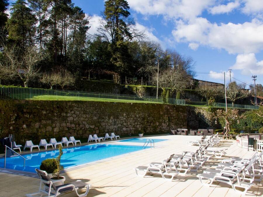 Piscina com espreguiçadeiras e um muro de pedra.