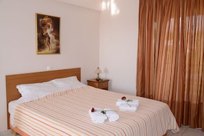 Uma cama bem arrumada com roupa de cama listrada, uma mesa de cabeceira com abajur e um quadro na parede.