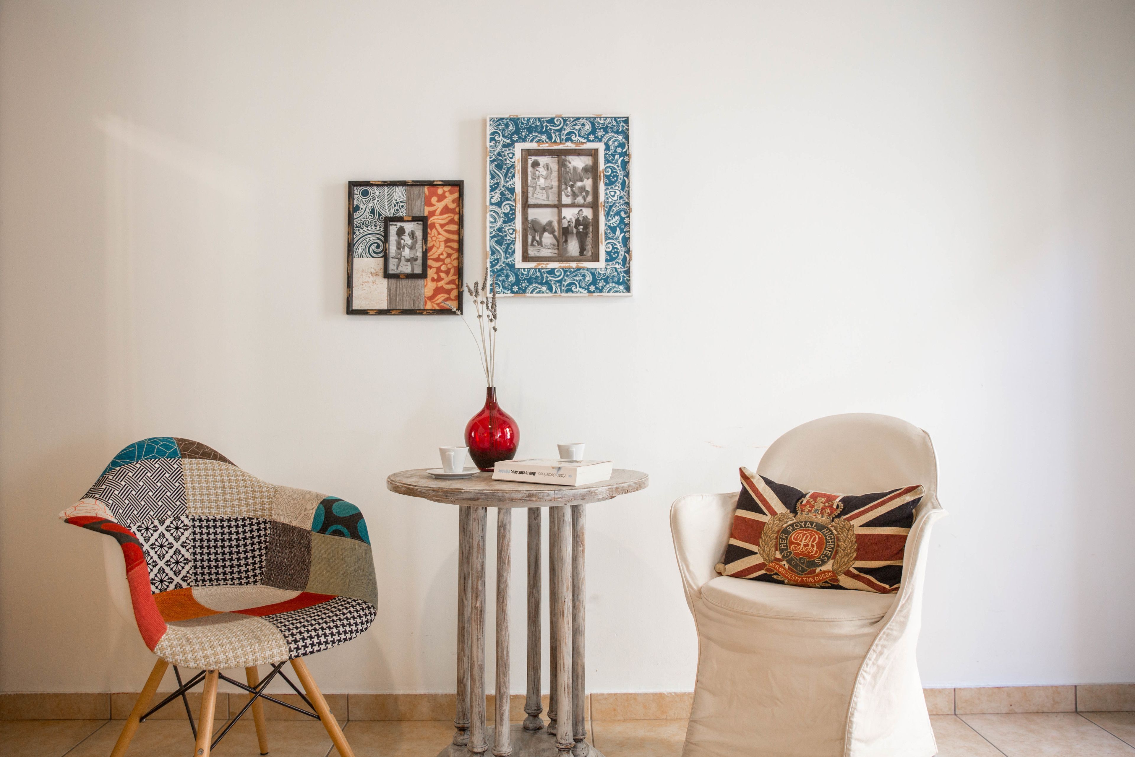 Quarto com uma mesa redonda, duas cadeiras e duas quadros na parede.