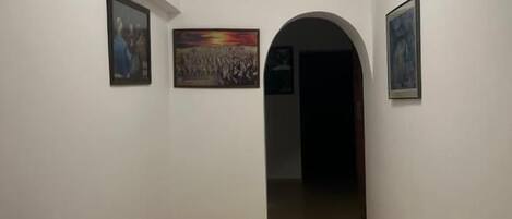 Um corredor com paredes brancas, piso ladrilhado e quadros nas paredes.