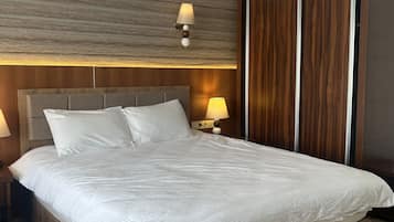 Uma cama bem arrumada com roupa de cama branca, cabeceira de madeira e ar condicionado fixado na parede.