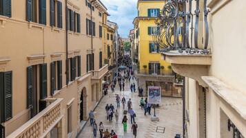 Rua para pedestres repleta de edifícios históricos, com uma multidão de pessoas e um letreiro chamativo para 'Water & Wine'.