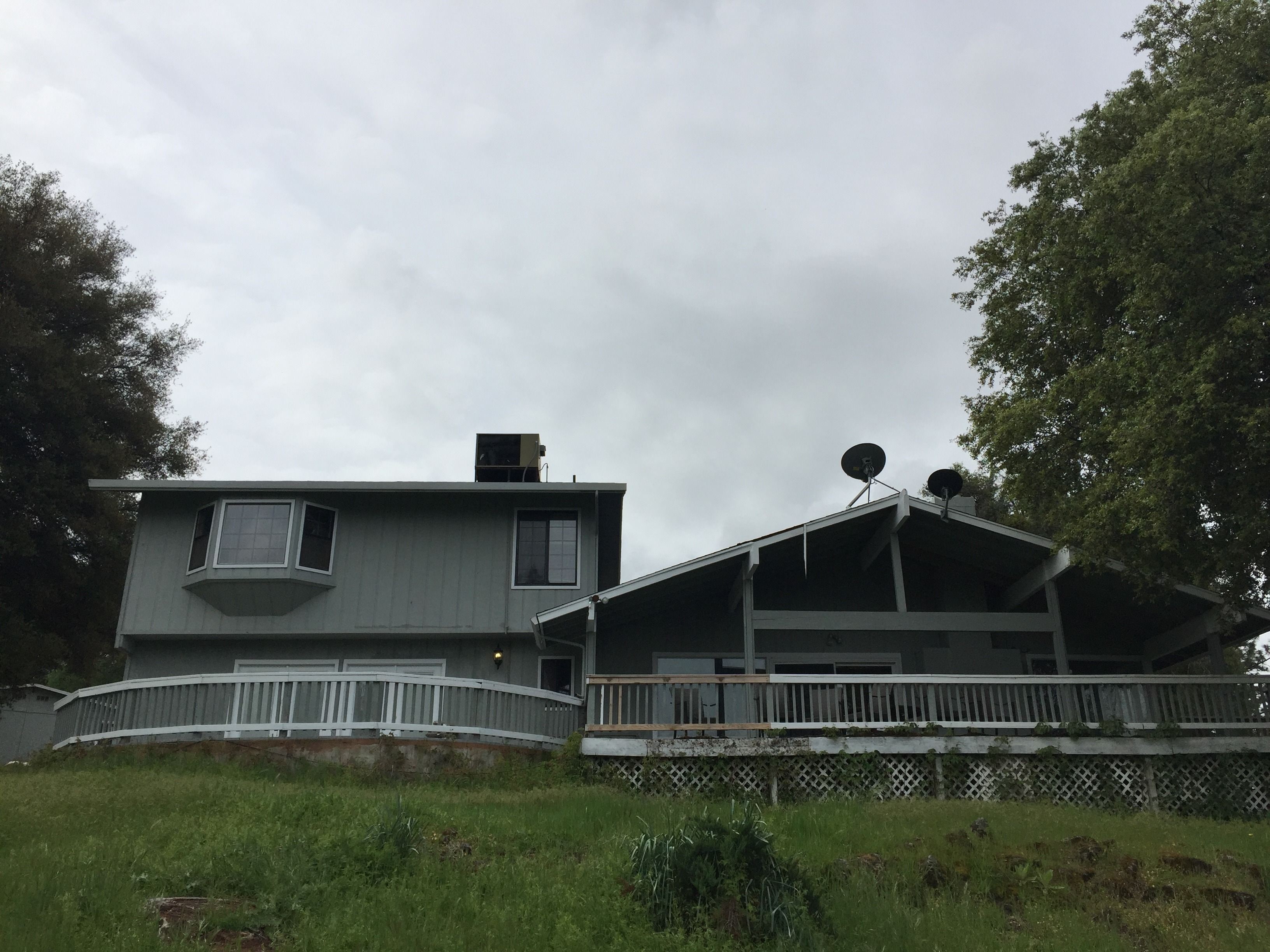 Uma casa de dois andares com varanda coberta e quintal cercado.