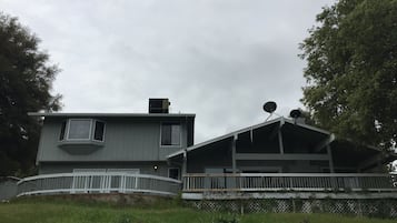 Uma casa de dois andares com varanda coberta e quintal cercado.