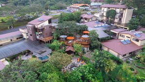 Área residencial com várias casas, algumas com varandas e painéis solares, cercada por vegetação exuberante.