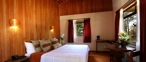 Um quarto com painéis de madeira, uma cama, uma mesa e uma janela com cortinas.