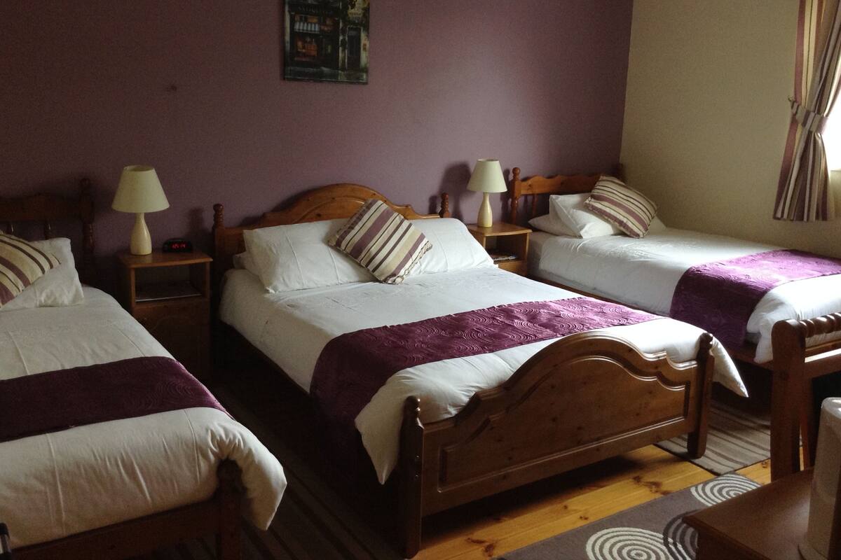 Quarto de hotel com duas camas de madeira, cada uma com uma mesa de cabeceira, um abajur e uma almofada.