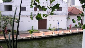 Um canal com um edifício branco ao fundo, plantas em vasos e vista clara da água.