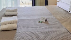 Quarto de hotel com cama, uma pequena mesa, uma cadeira e vista para o verde lá fora.