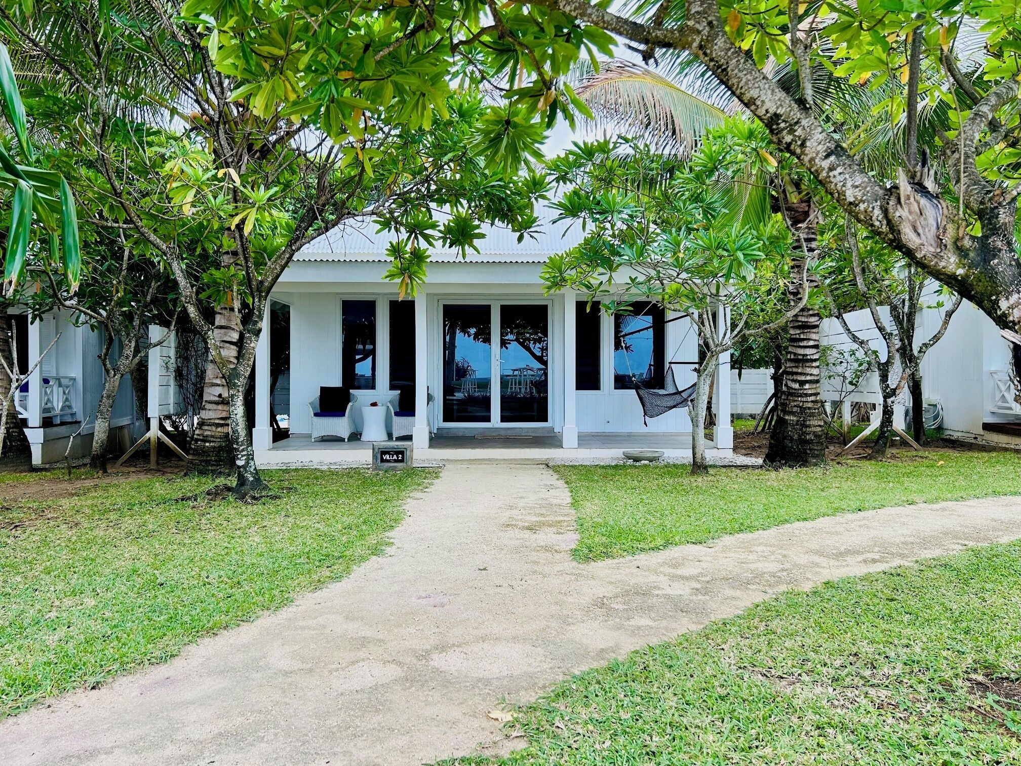 Uma villa com entrada pavimentada, varanda coberta e rede.