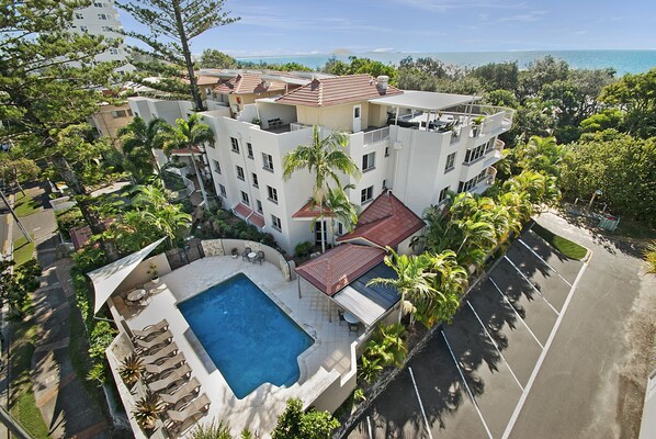 Um hotel com vários andares, piscina, área de estar externa e vista para o oceano.