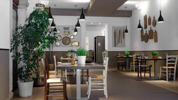 Uma sala de jantar moderna com uma mesa central, cadeiras, luminárias pendentes e plantas em vasos.