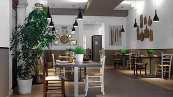 Uma sala de jantar moderna com uma mesa central, cadeiras, luminárias pendentes e plantas em vasos.
