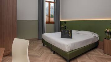 Quarto de hotel com uma cama, uma cadeira, uma mesa de cabeceira, uma luminária e vista de uma cúpula pela janela.