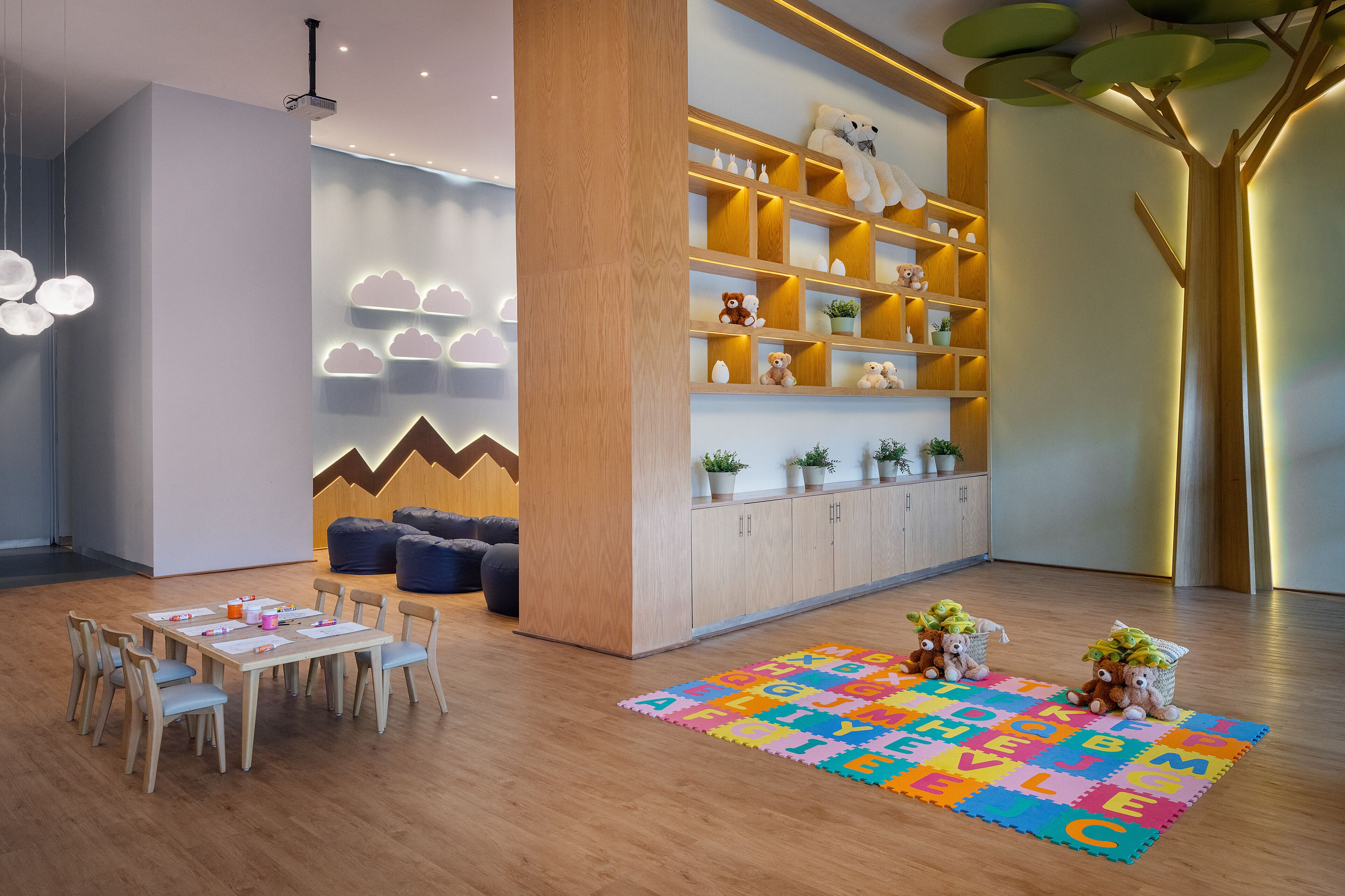 Uma área de recreação infantil moderna com uma mesa de madeira, cadeiras e um tapete colorido com o alfabeto.