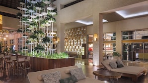 Um hall espaçoso com design moderno, apresentando uma área de estar com sofás e um bar com banquetas.