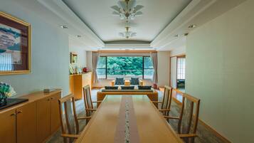 Uma sala de jantar com uma mesa comprida, cadeiras, um banco e um ventilador de teto.