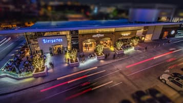 Vista aérea do Biergarten com mesas ao ar livre e entrada bem iluminada.