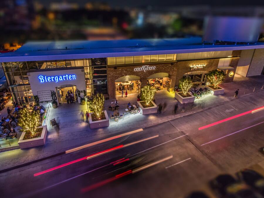 Vista aérea do Biergarten com mesas ao ar livre e entrada bem iluminada.