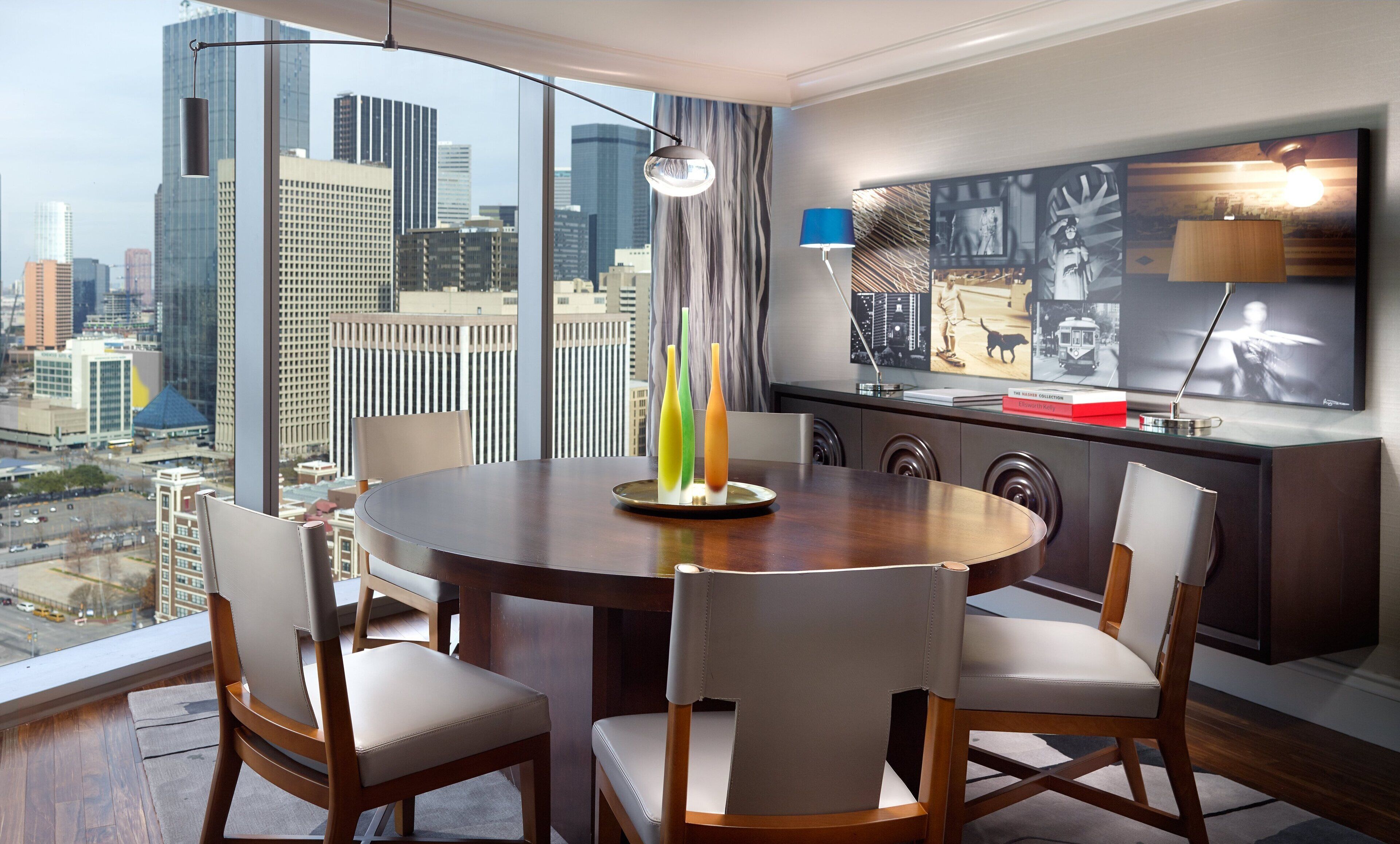 Uma área de refeições moderna com uma mesa redonda, quatro cadeiras, vista para a cidade e decoração contemporânea.