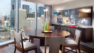 Uma área de refeições moderna com uma mesa redonda, quatro cadeiras, vista para a cidade e decoração contemporânea.
