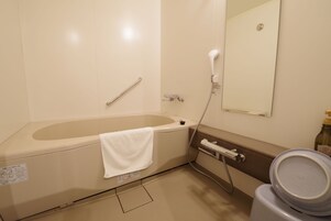 Uma casa de banho com banheira, secador de mãos, toalha e sanita.
