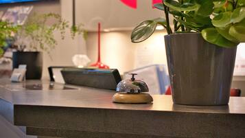 Uma mesa de recepção com uma planta em vaso, um telefone e um sino.