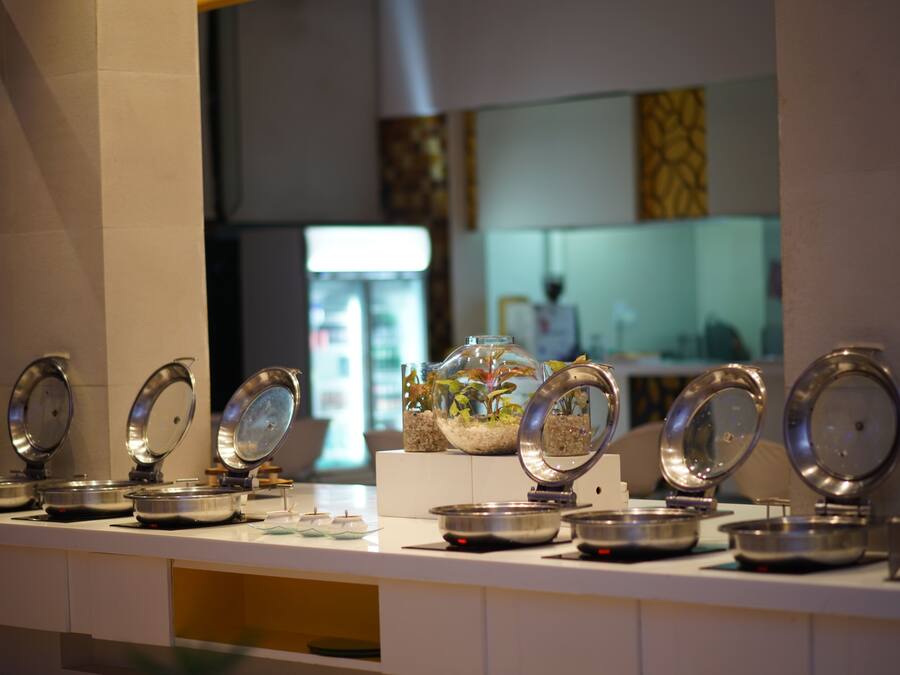 Disposição de buffet com várias estações de serviço, um arranjo central de objetos decorativos e uma visão rápida de uma área de cozinha ao fundo.