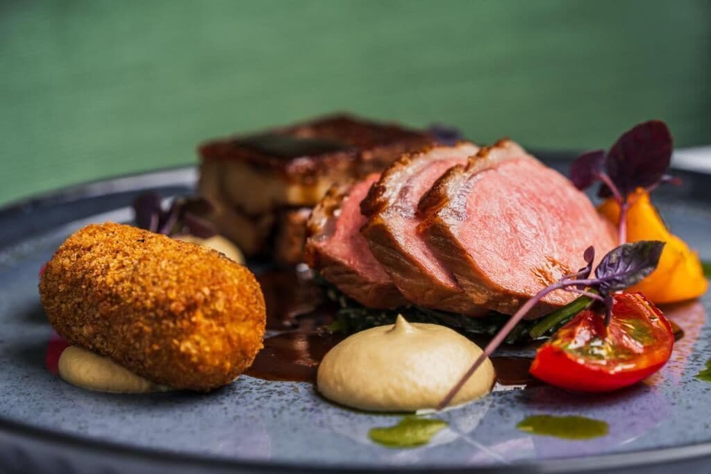 Prato com carne, um acompanhamento empanado e legumes.