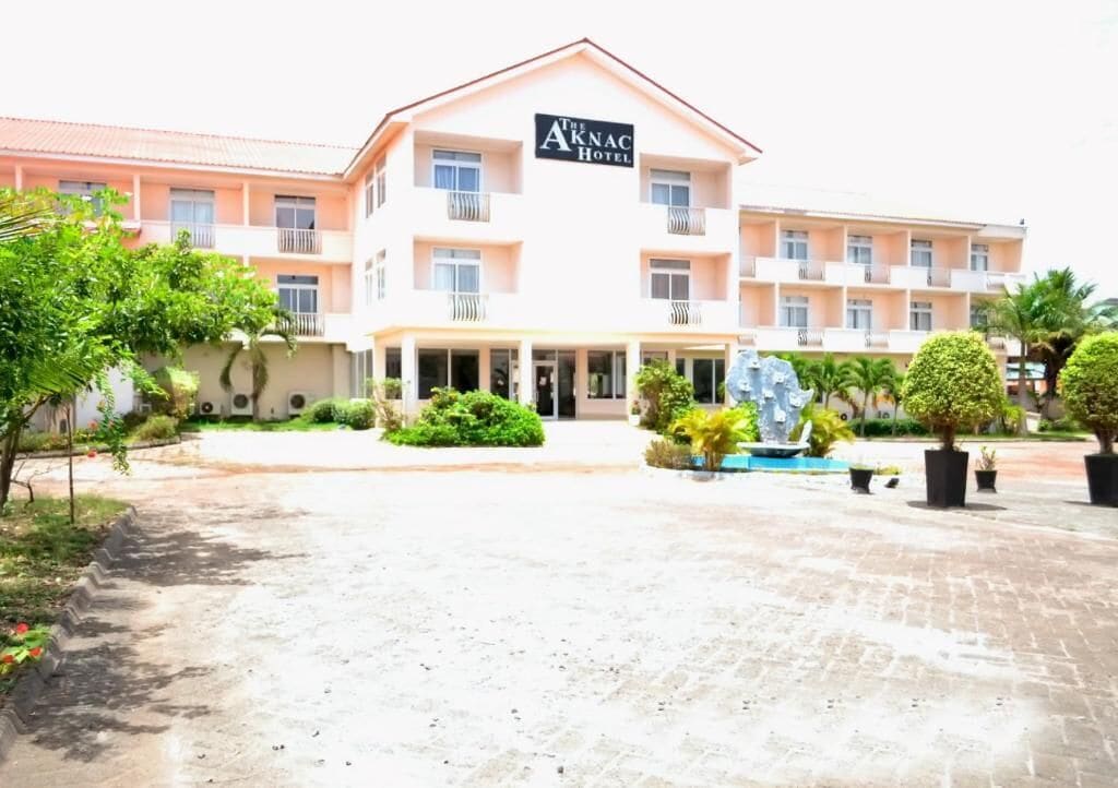 Hotel com vários andares, entrada central, varandas e um pátio ajardinado.