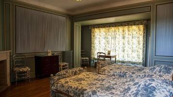 Quarto com duas camas, uma cômoda, uma cadeira e uma mesa.