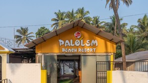 Um resort à beira-mar chamado Palolsem, com fachada amarela e uma placa indicando que é um resort de praia.