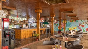 Um restaurante com interiores em madeira, área de bar e um mural na parede.