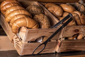 Uma caixa de madeira cheia de diferentes tipos de pão, incluindo pães e pãezinhos.