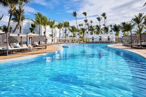 Piscina com espreguiçadeiras e palmeiras.