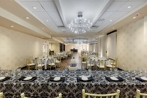 Uma sala de banquetes com mesas redondas, cadeiras douradas e um display central de bolo.